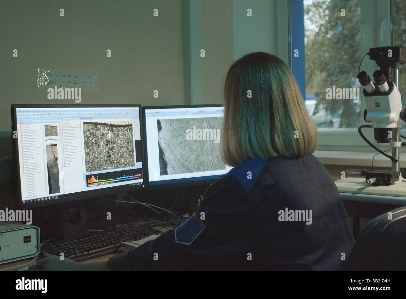 A female cameraman sits behind monitors in a science center Stock Photo ...