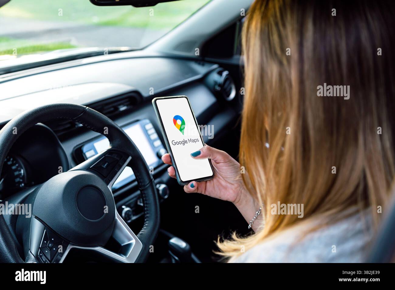 Woman in a car looking her phone with Google Maps in the screen ...