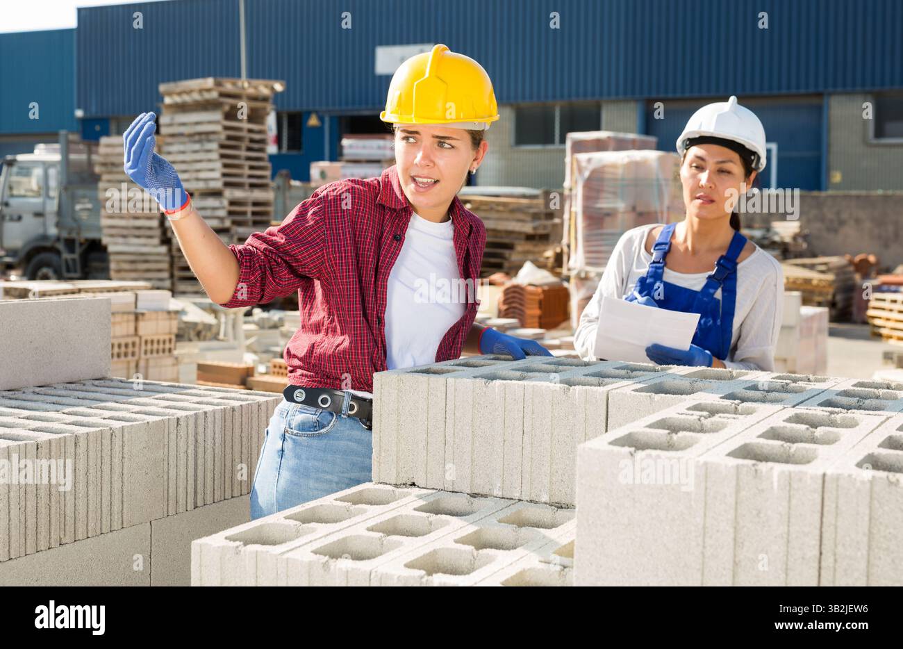 Female builders with hollow concrete blocks in outdoor warehouse Stock ...