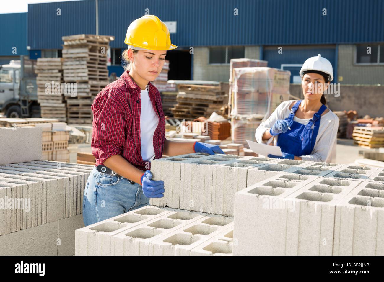 Construction shop worker stacks bricks on an open-air site Stock Photo ...