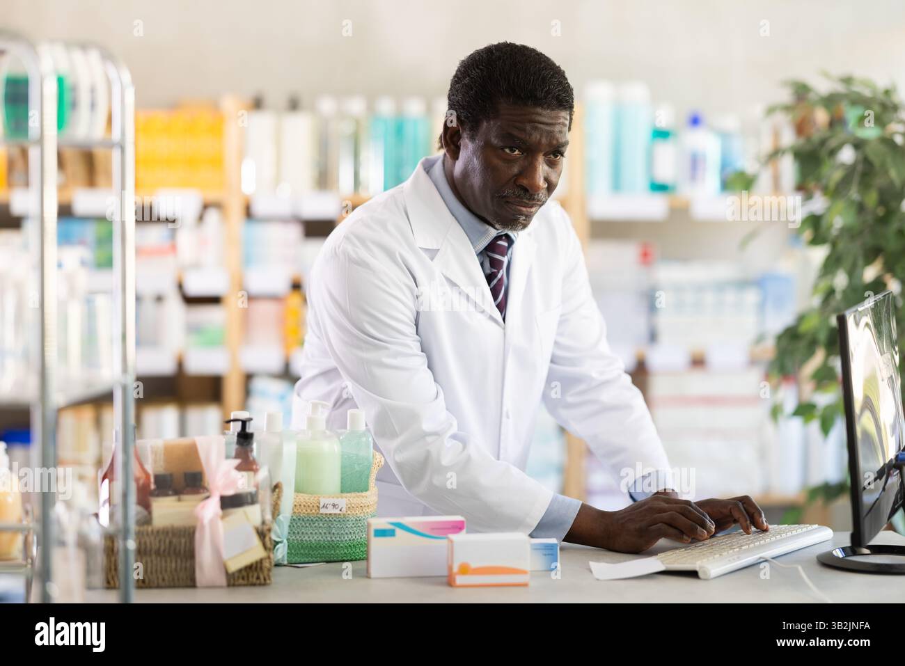 African man pharmacist uses computer at workplace Stock Photo - Alamy