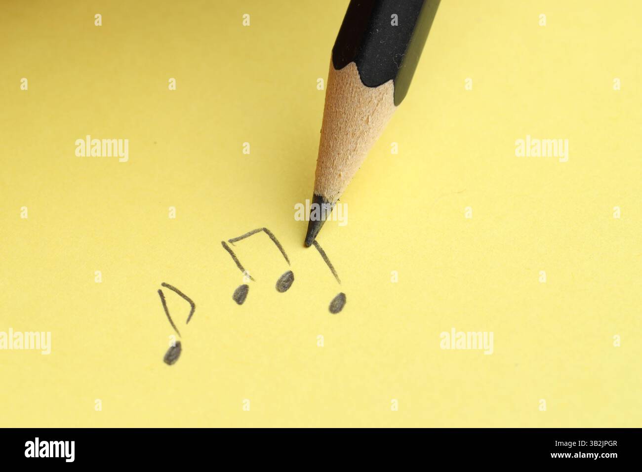 Drawing musical notes with graphite pencil on yellow background ...