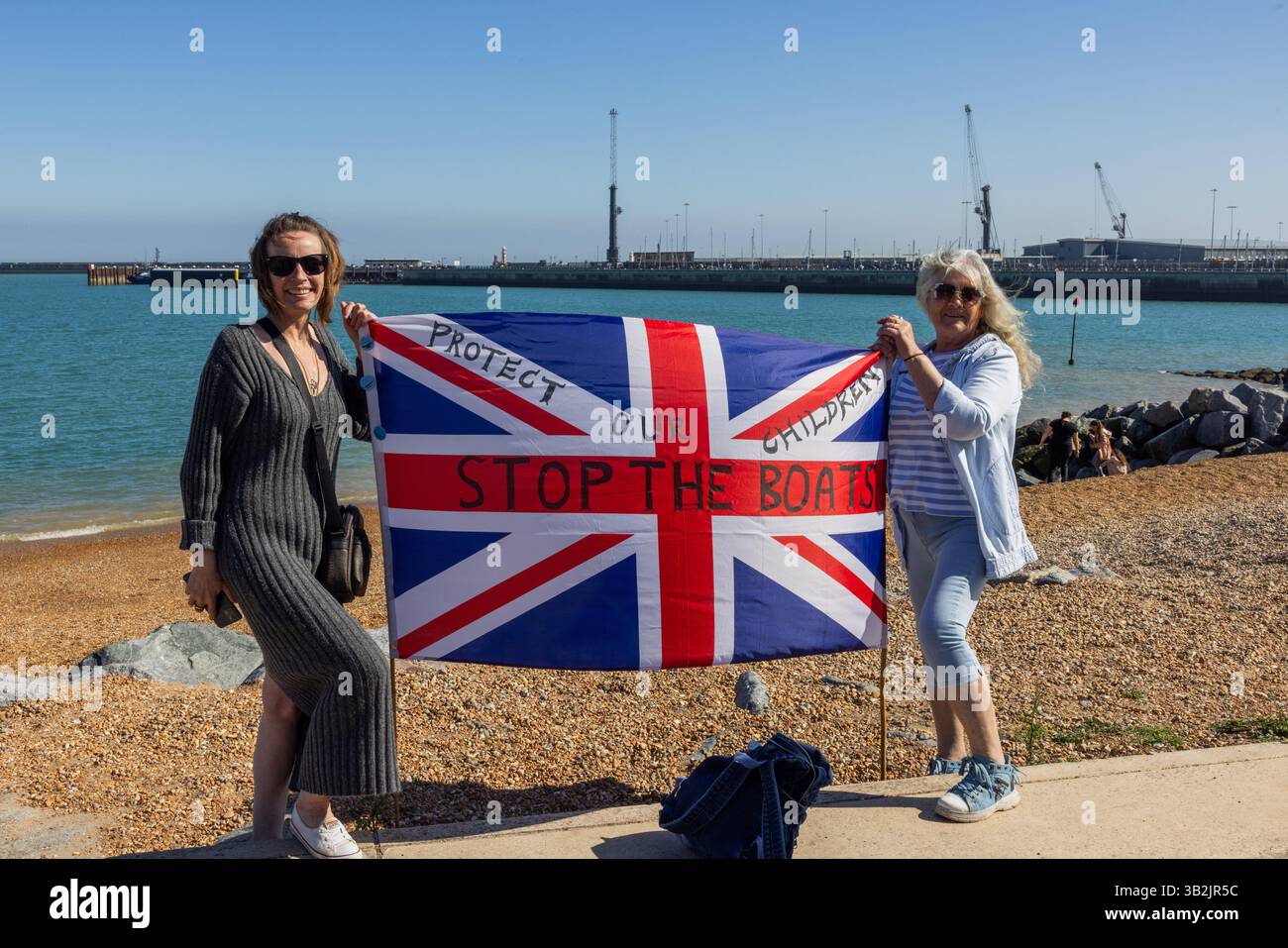 Dover, UK. 27 APR, 2025. Two people hold "Stop the boats" flag on the ...