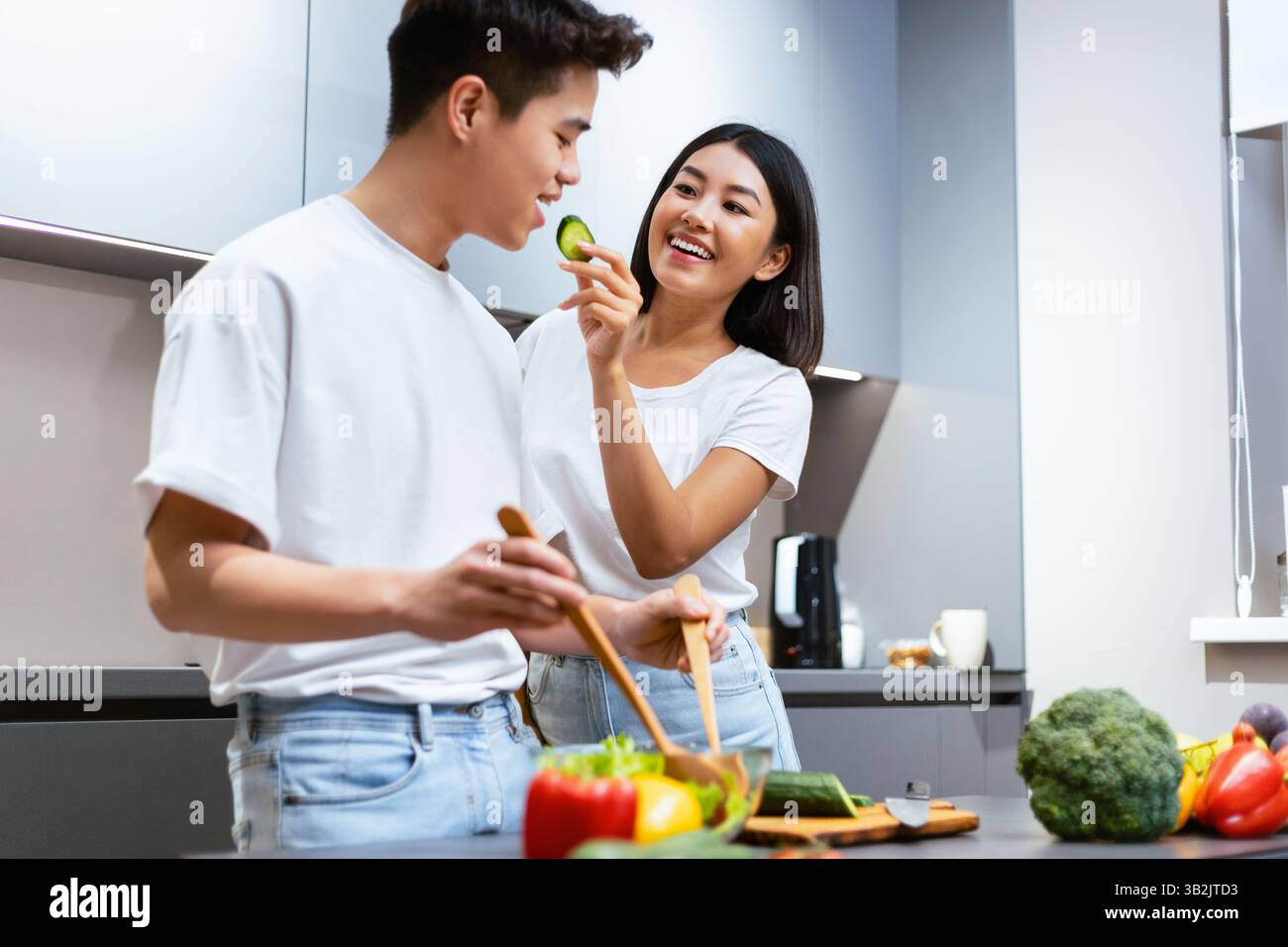 Japanese Couple Tasting Food While Cooking Dinner Together In Kitchen ...