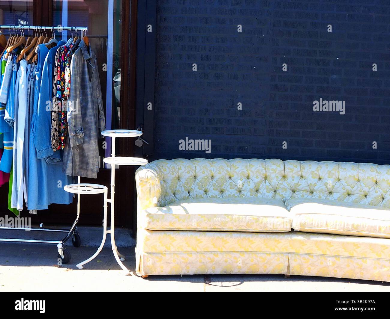 Vintage sofa and second-hand clothes outside thrift shop in ...