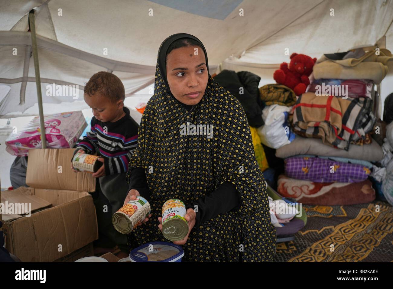 Shaima Al-Louh, 24, stores canned food for her children at her tent a ...