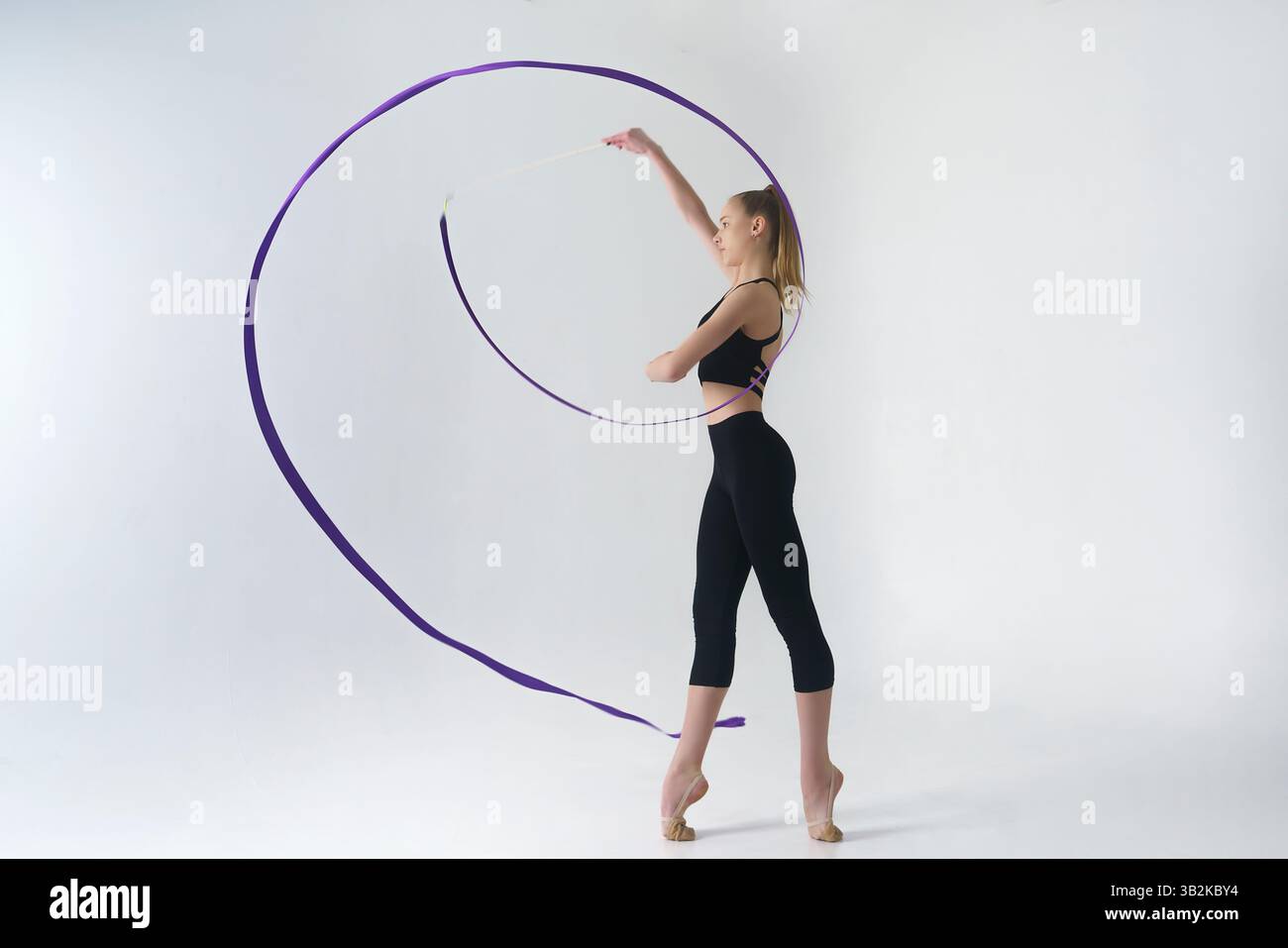 a young gymnast in a photo studio shows the elements of exercises with ...