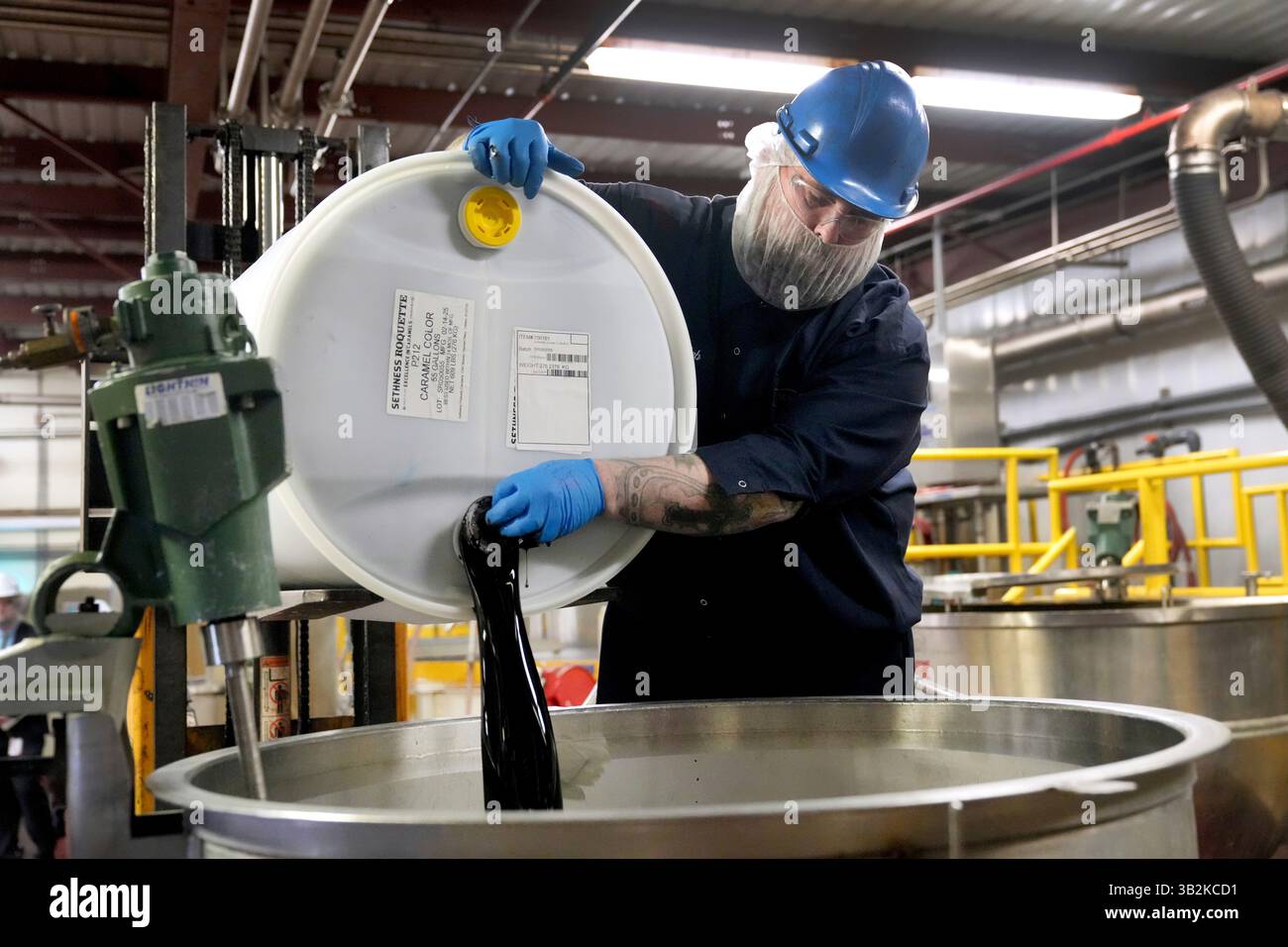 Caleb Whorl pours a container of caramel coloring into a vat to be ...
