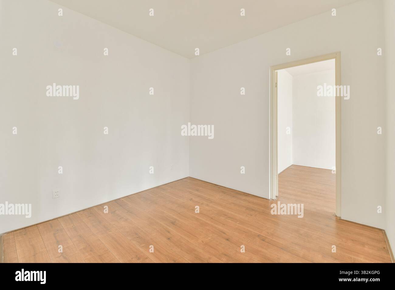 A spacious, empty room featuring a wooden floor and a doorway leading ...