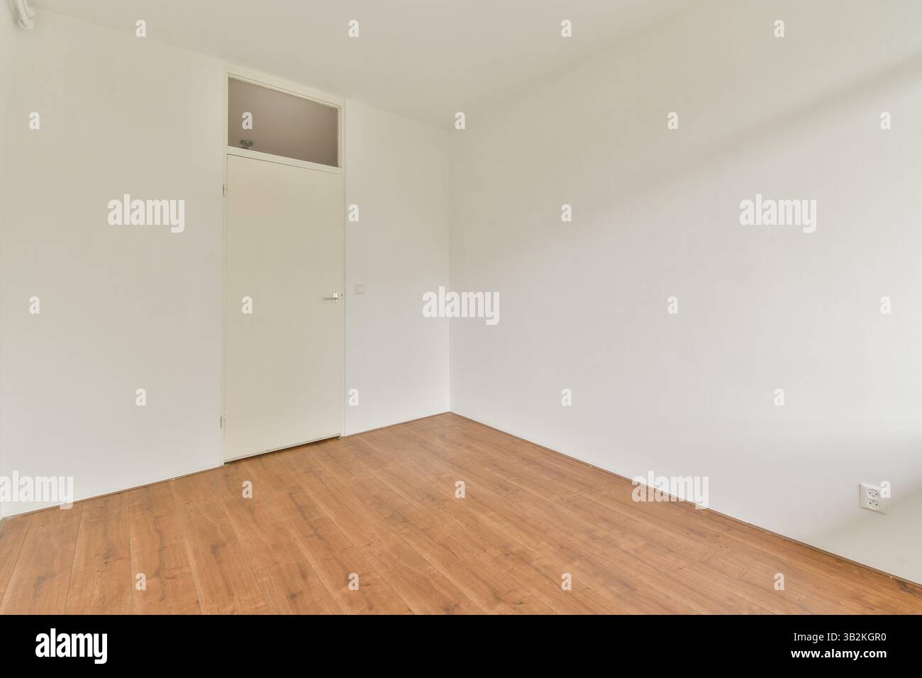 An unoccupied minimalist room featuring plain white walls and a wooden ...