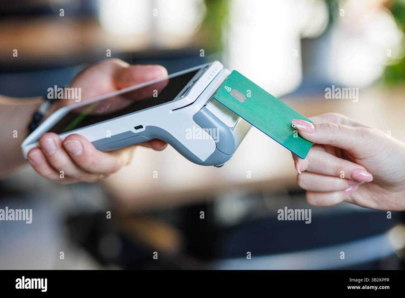 Close-up of female hand holding green contactless credit card paying at ...