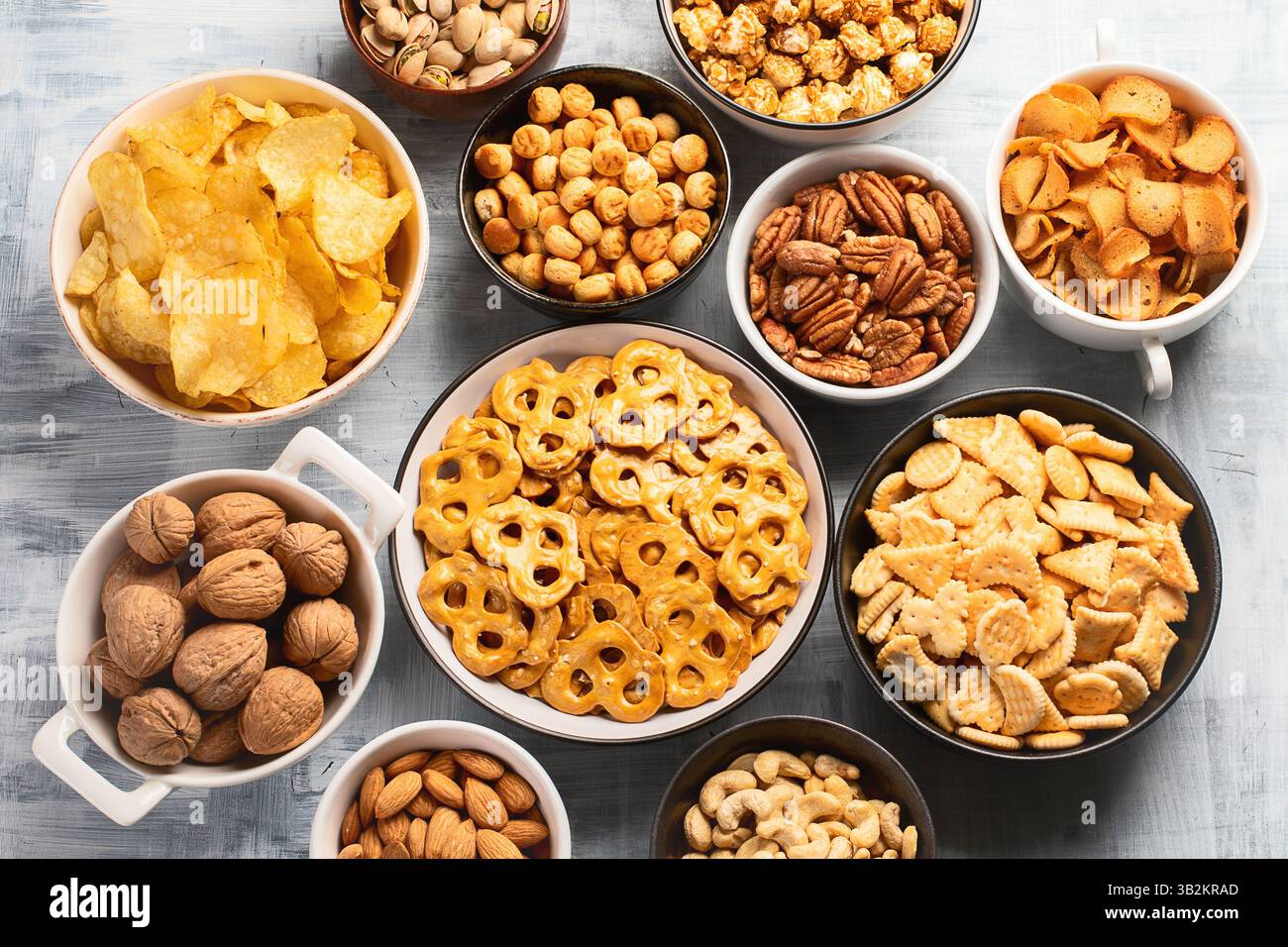 Different kinds of snacks, chips, nuts, popcorn and cookies on a grey ...