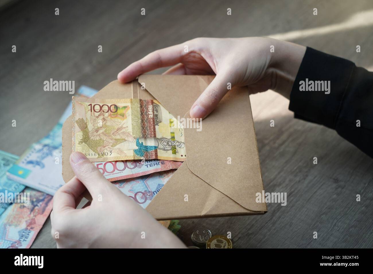 Tenge banknotes of different denominations in an envelope in his hands ...