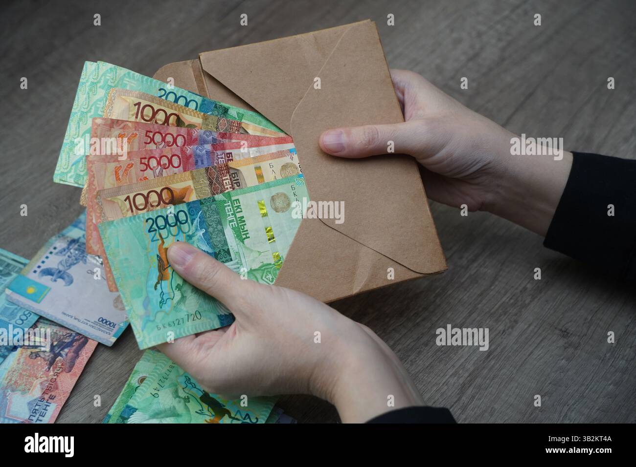Tenge banknotes of different denominations in an envelope in his hands ...