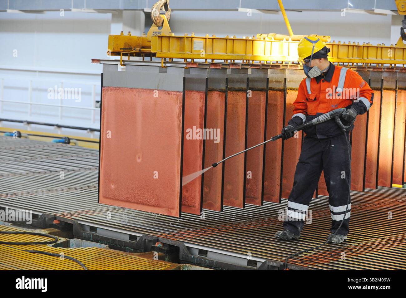 A worker washes plates with cathode copper at an industrial plant Stock ...