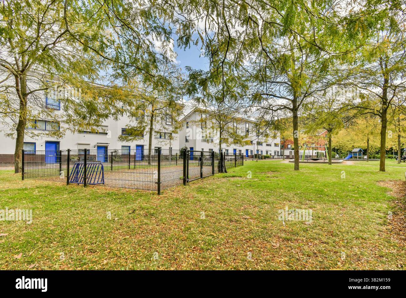 A serene residential playground surrounded by lush greenery and modern ...