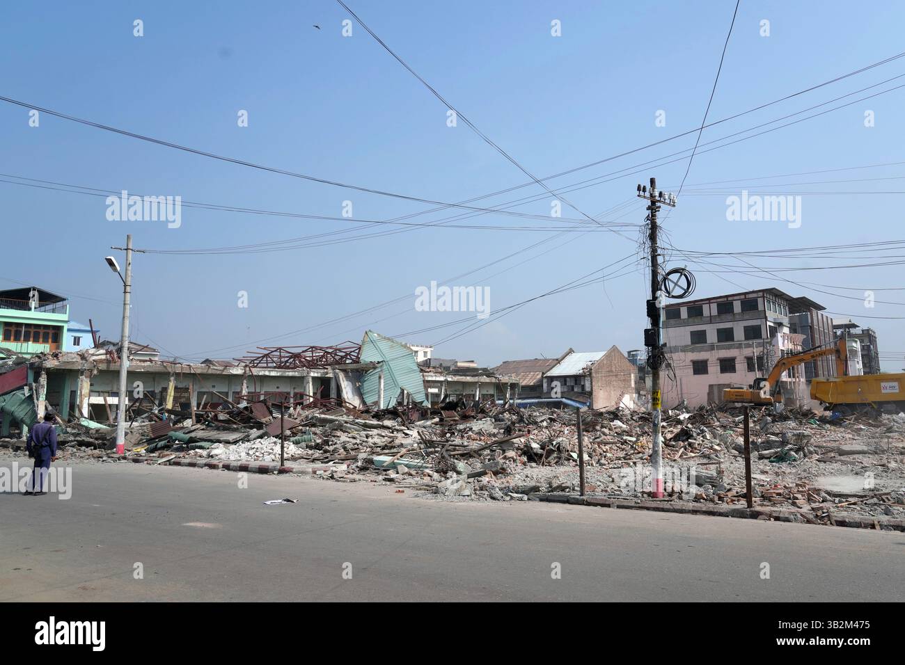 A volunteer drives a backhoe to clear debris of a building at a market ...