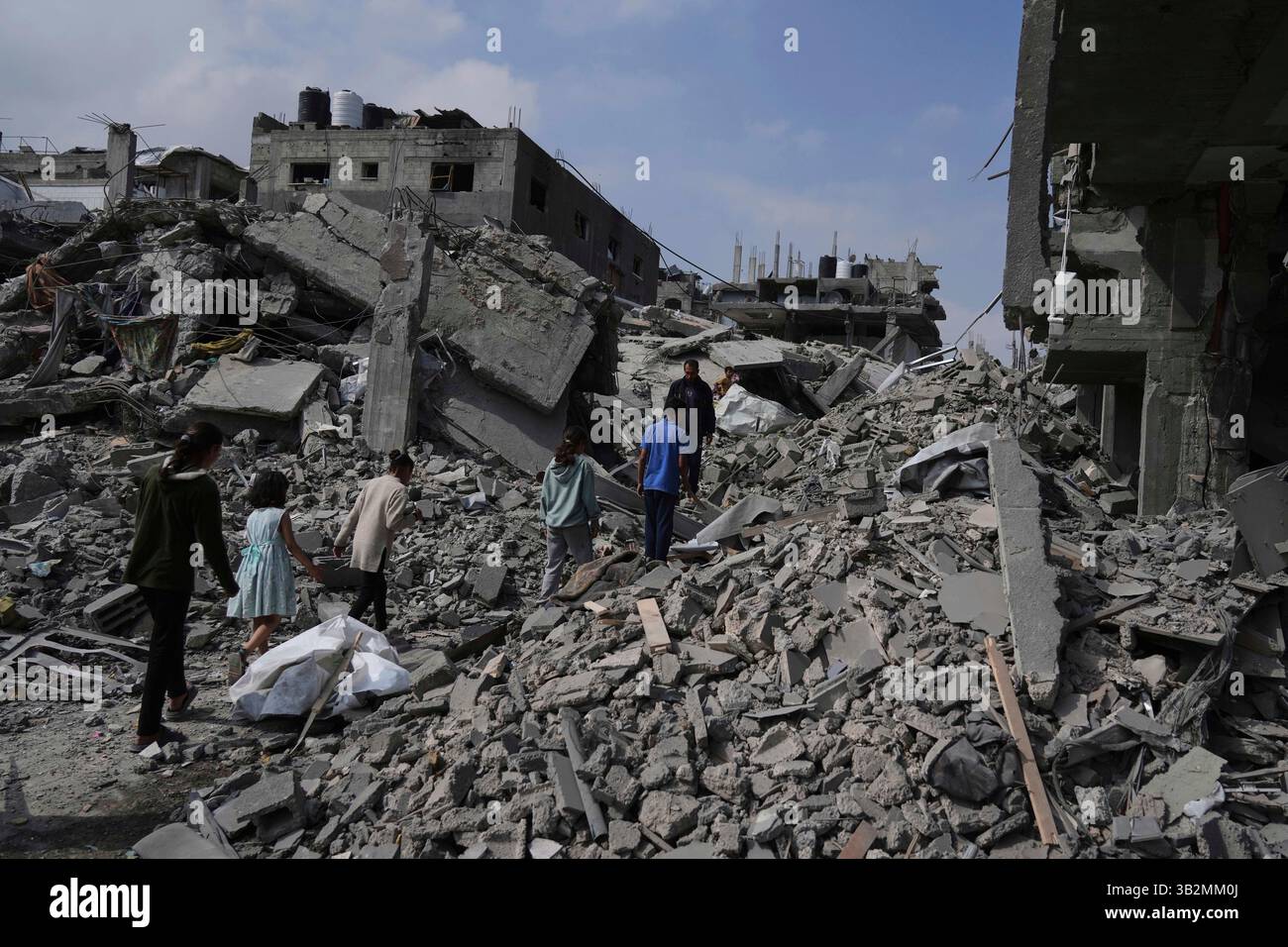 Palestinians walk in the rubbles after an Israeli army airstrike in ...