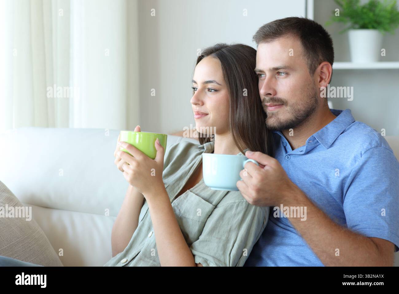 Relaxed couple drinking and looking through the window sitting on a ...