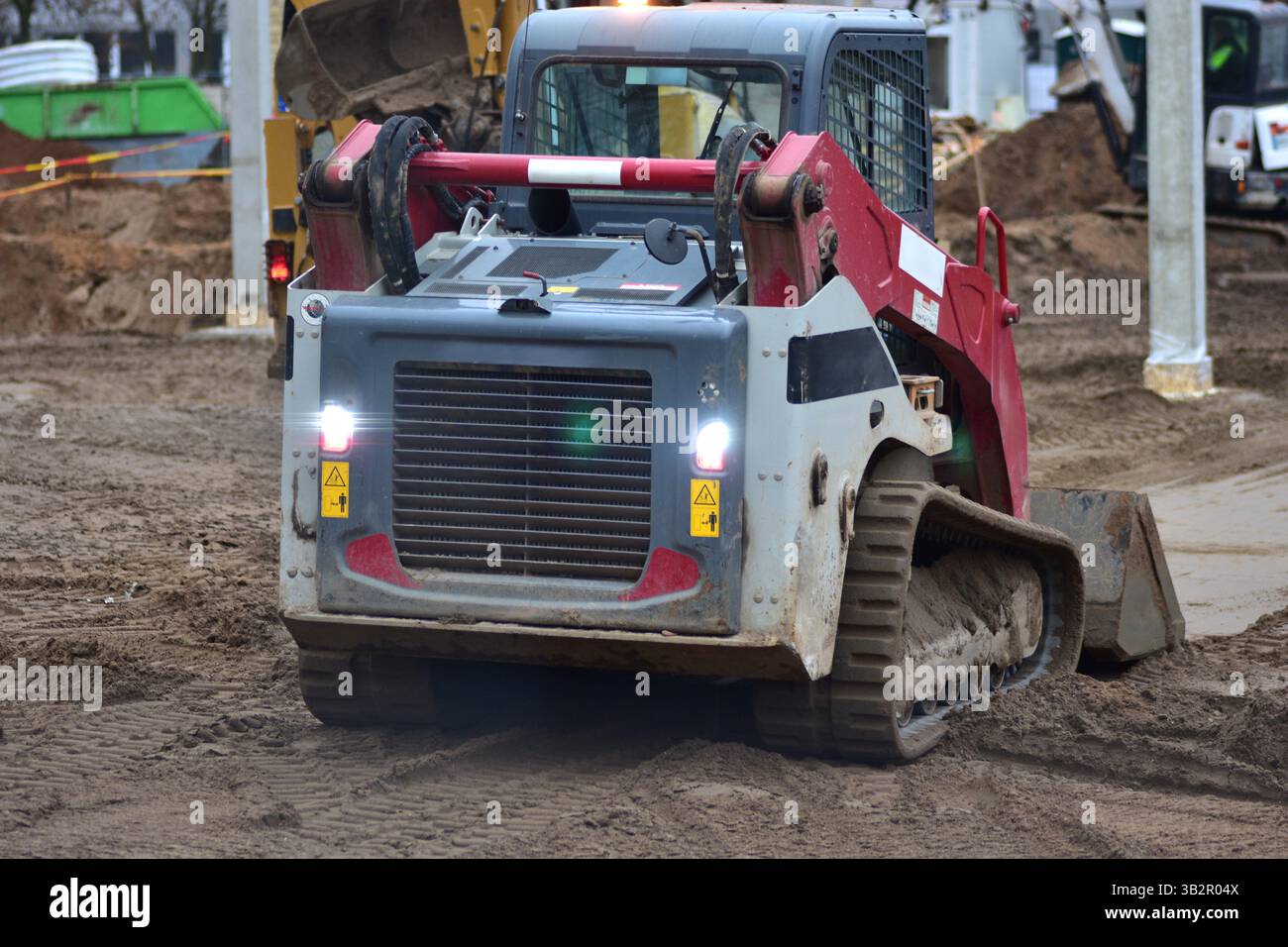 Mini caterpillar excavator digging and pushing ground in big ...