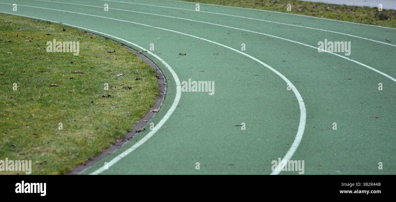 Green running track curve with white lines and green grass in the sides ...