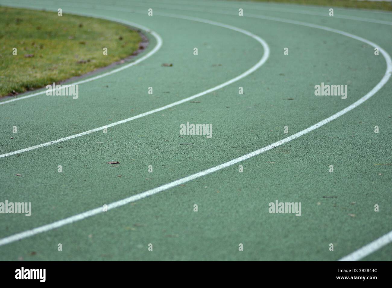 Green running track curve with white lines and green grass in the sides ...