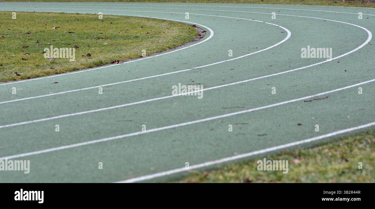 Green running track curve with white lines and green grass in the sides ...