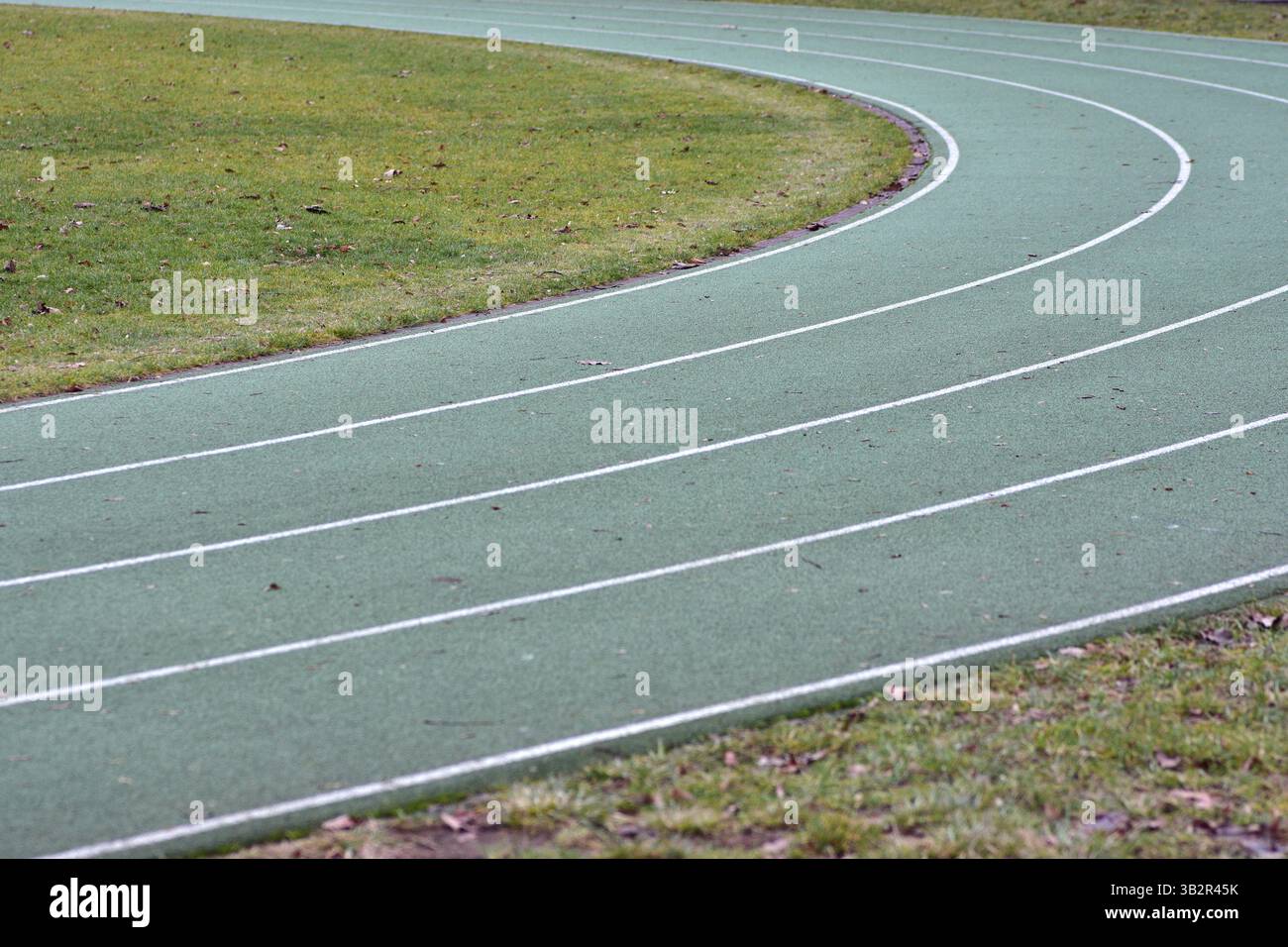 Green running track curve with white lines and green grass in the sides ...