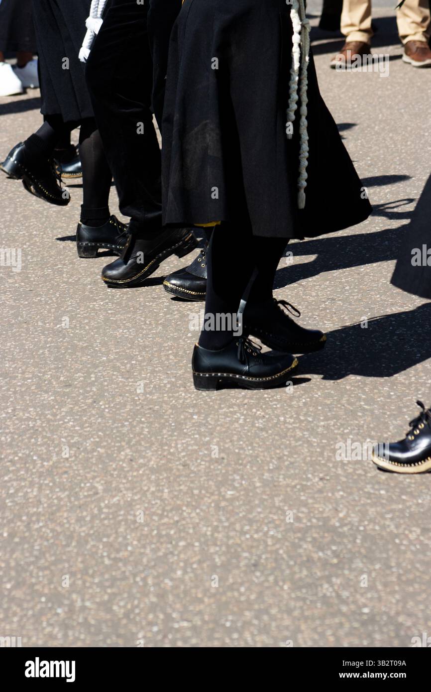 dancing feet in black shoes and clogs and black stockings on a tarmac ...