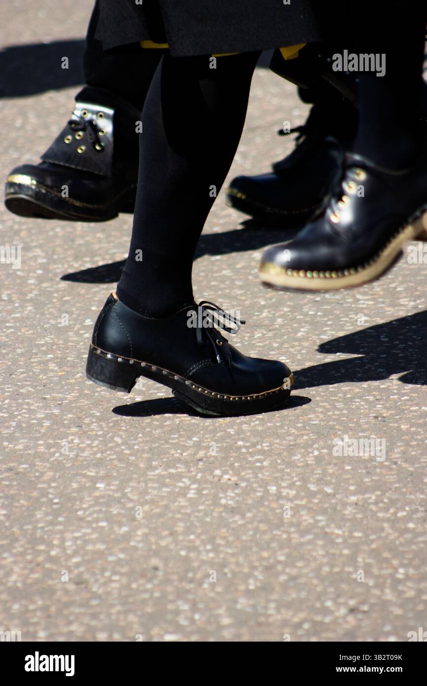 dancing feet in black shoes and clogs and black stockings on a tarmac ...