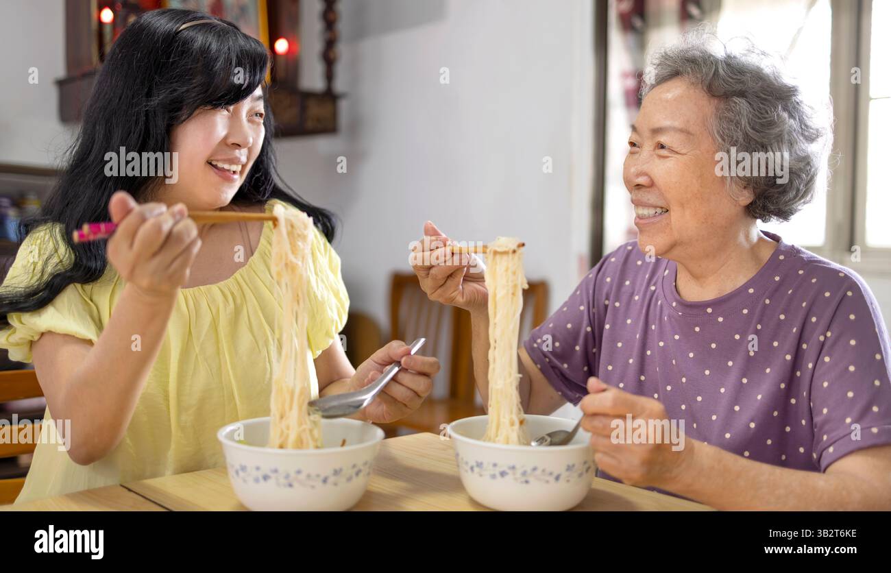 Happy elderly mother and daughter eating noodles at home Stock Photo ...