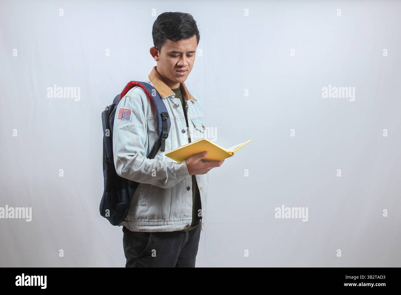 student wearing denim jacket carrying bag and reading book isolated on ...