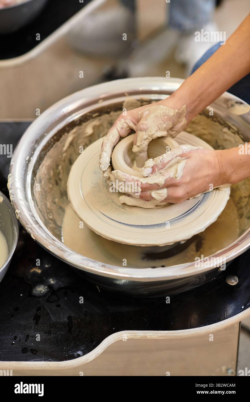 Hands expertly shape clay on a pottery wheel in a bright and inspiring ...