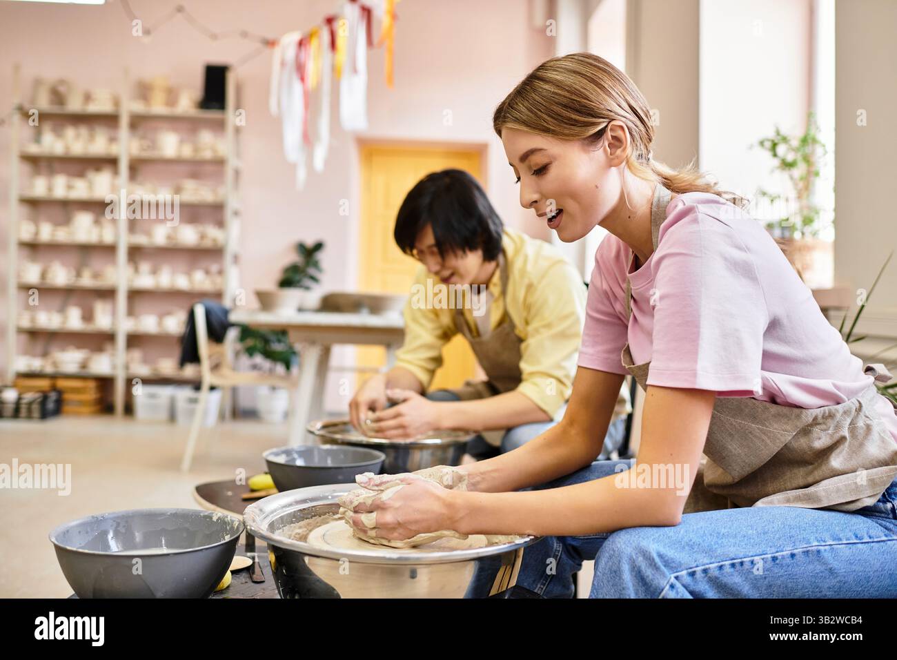 A young couple enjoys pottery making, laughing and crafting their art ...