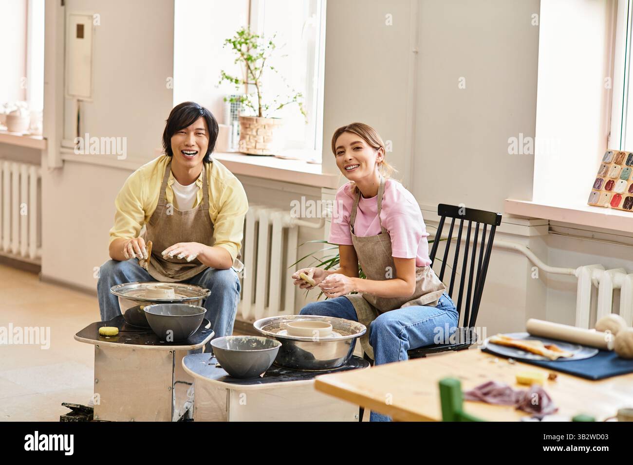 A young couple enjoys a fun and playful pottery session, laughing and creating together Stock ...