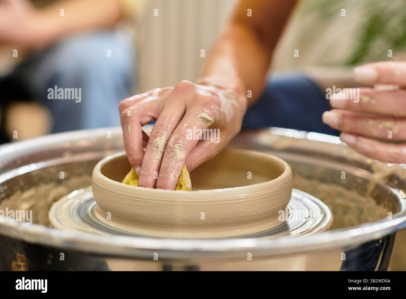 Hands expertly shape pottery with a sponge in a bright studio Stock ...