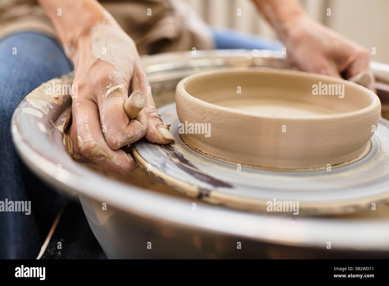 Hands expertly shape clay on the potters wheel in a bright and inviting ...