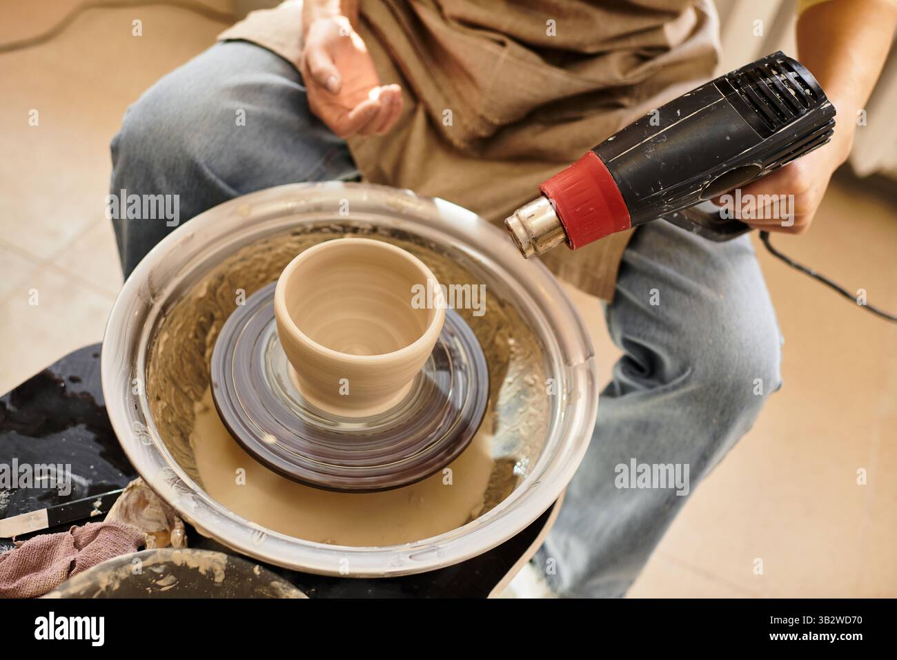 A potter skillfully shapes clay using a wheel and a heat tool in a ...