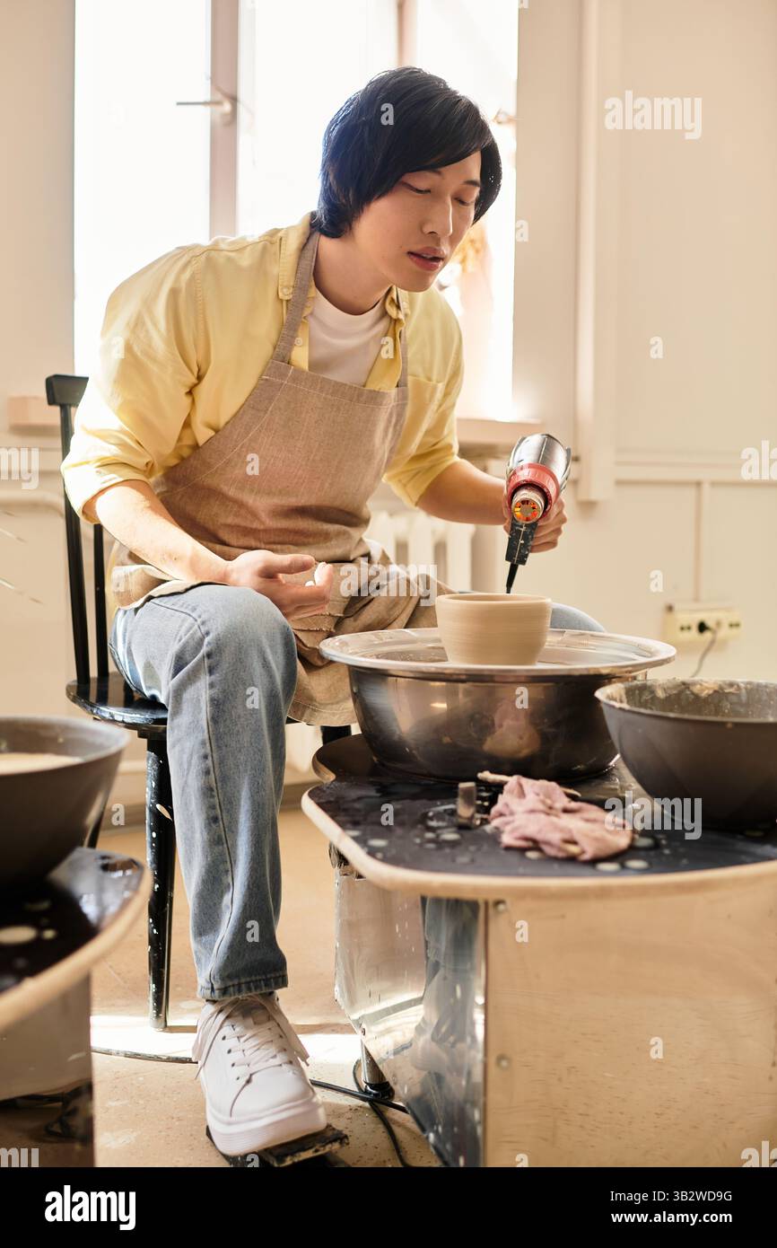 Focused artist shapes clay into unique pottery pieces in a bright ...