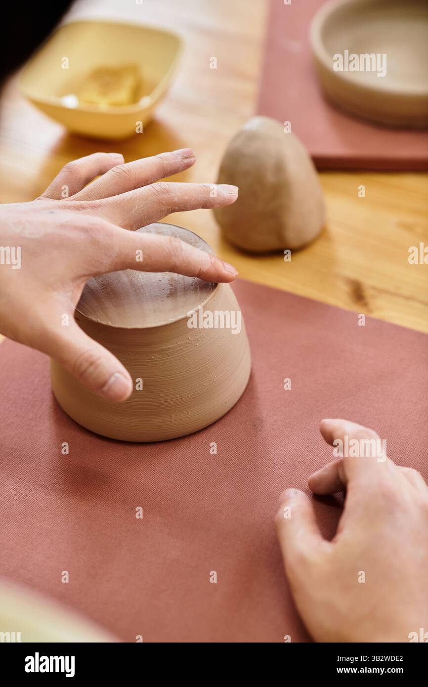Hands skillfully shape unglazed clay into beautiful pottery in a bright ...
