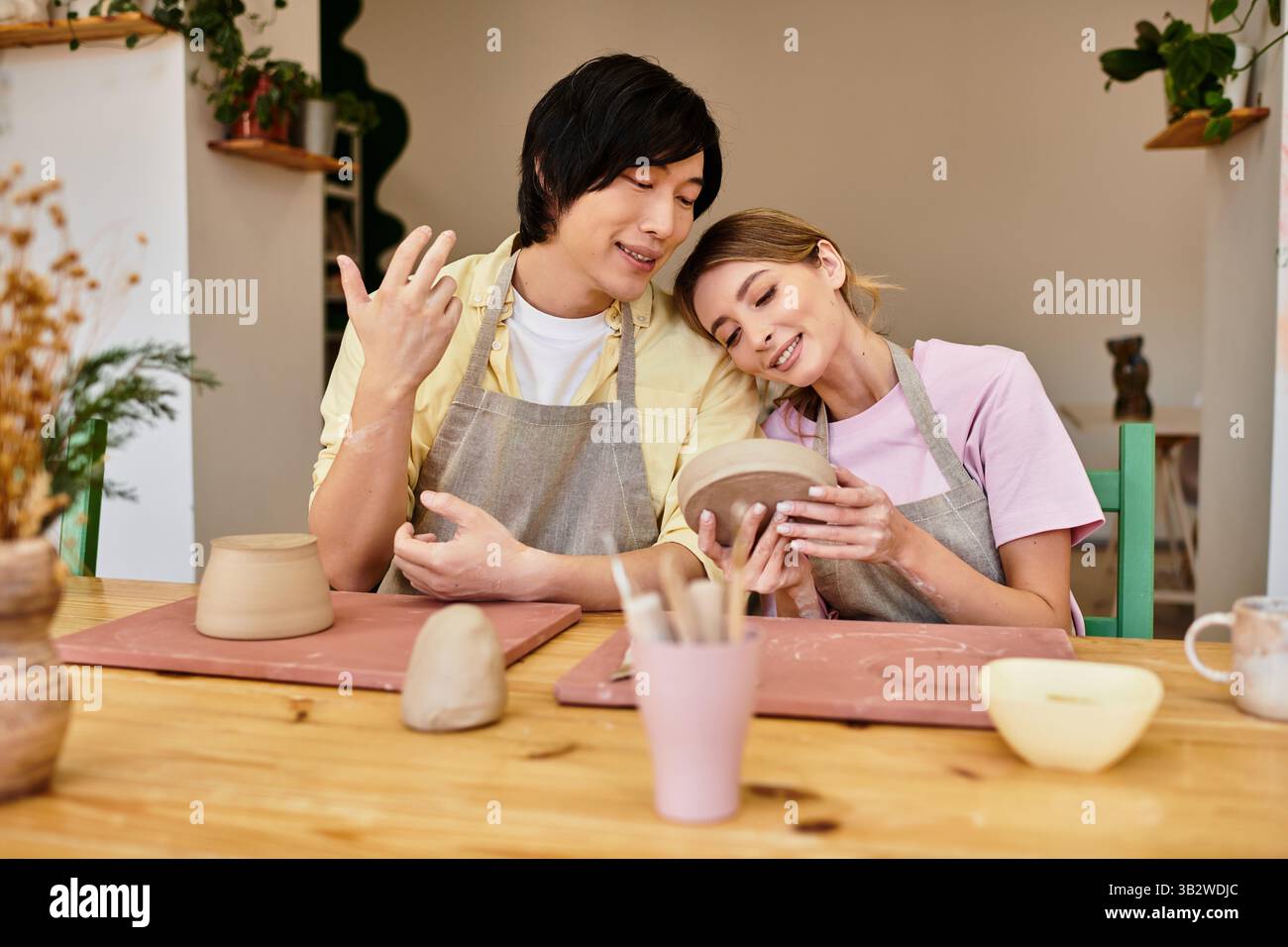 A young couple enjoys quality time while crafting pottery together in a ...