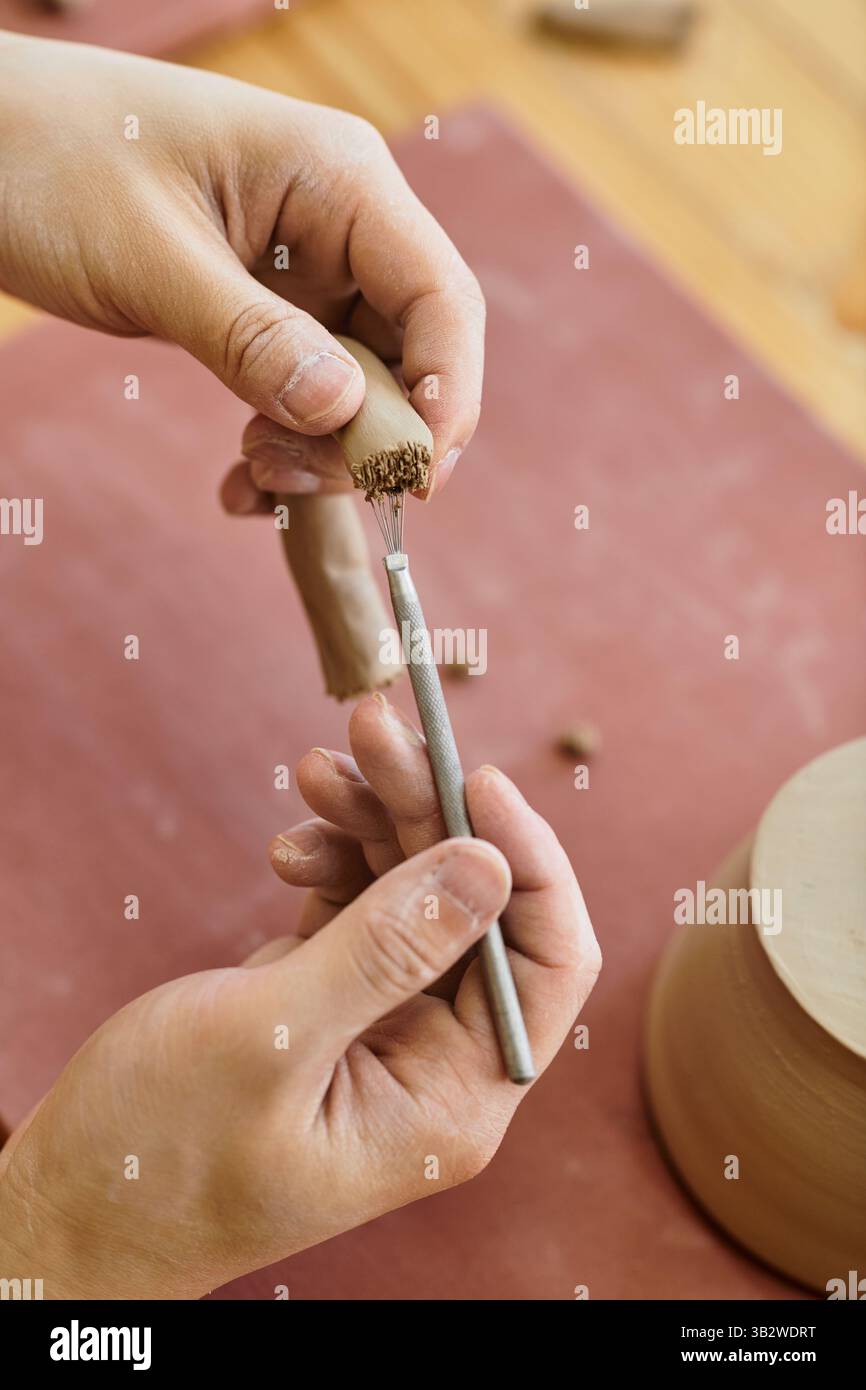Hands expertly shape clay in a bright, vibrant pottery studio full of ...