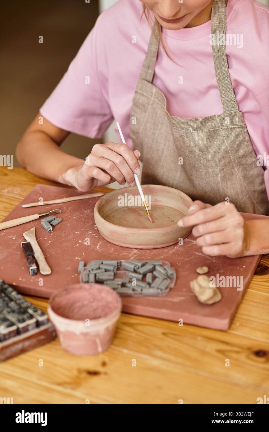 A dedicated artist brings life to clay with careful brush strokes in a ...