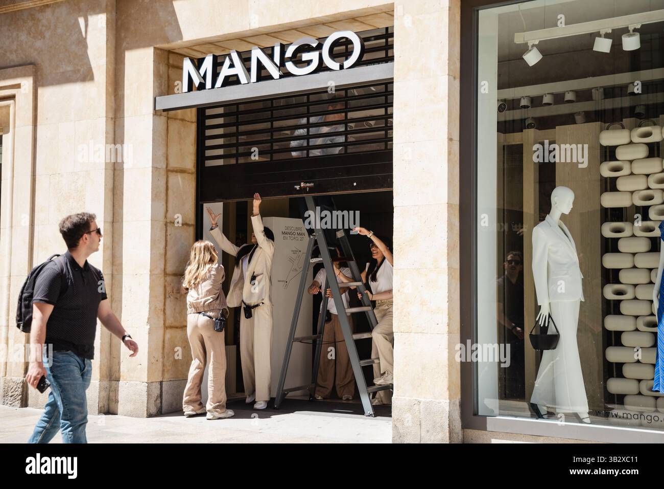 Several employees manually close the shutter of the Mango store in ...
