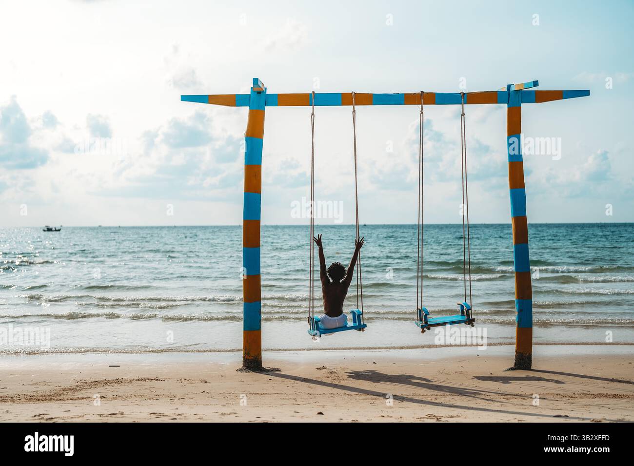 Man enjoys a peaceful moment of solitude on a beach swing, embracing ...