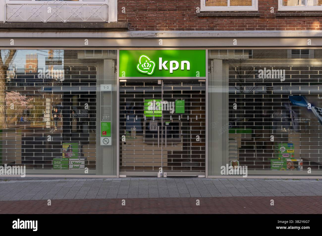 Closed KPN store with green logo and metal security gate, modern ...
