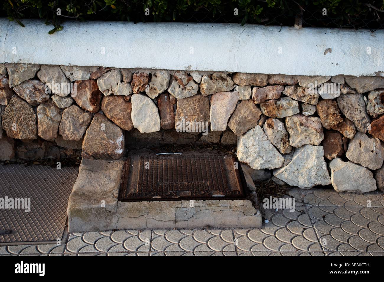 typical iron drain cover in Menorca and a dry stone wall Stock Photo ...