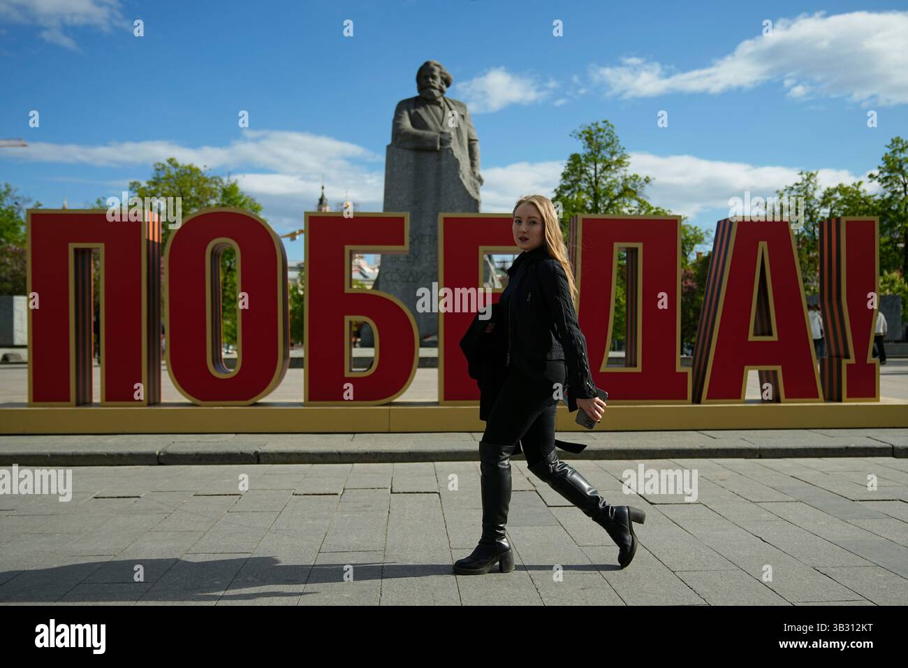 A woman walks next to an installation reading "Victory" In Russian ...