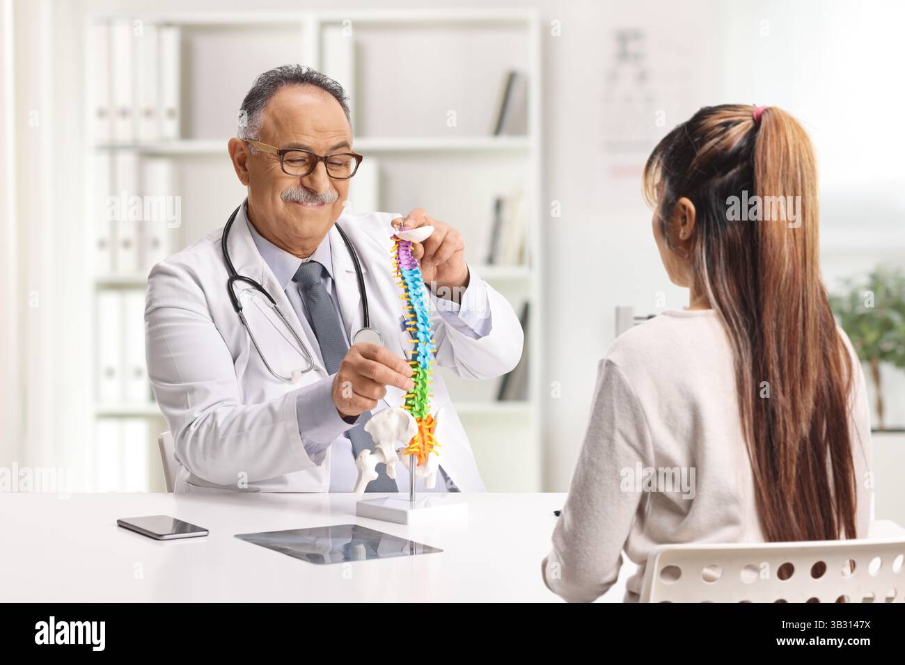 Mature male doctor explaining a cervical spine model to a female ...