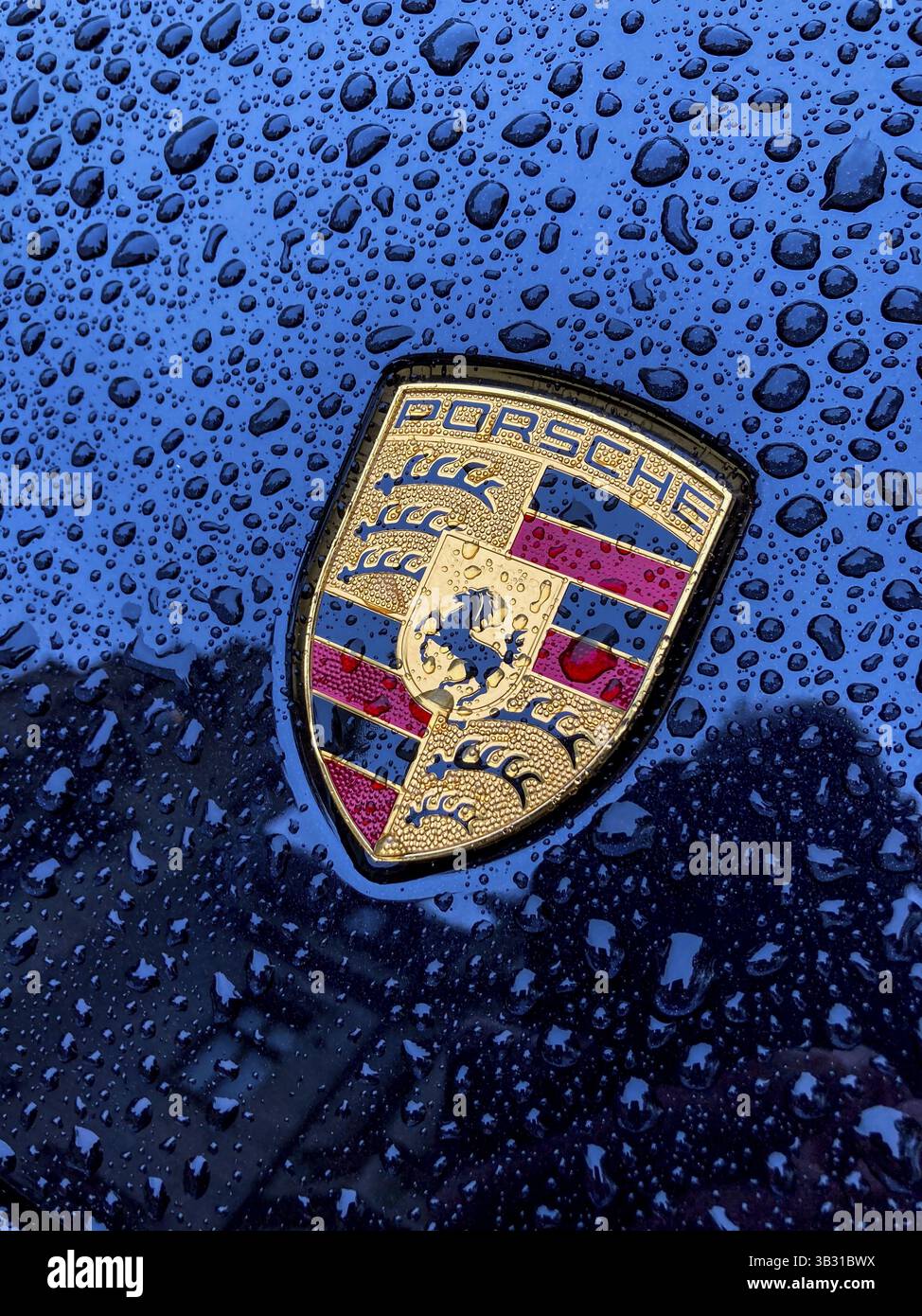 Porsche crest on navy blue bonnet of sports car with sparkling ...